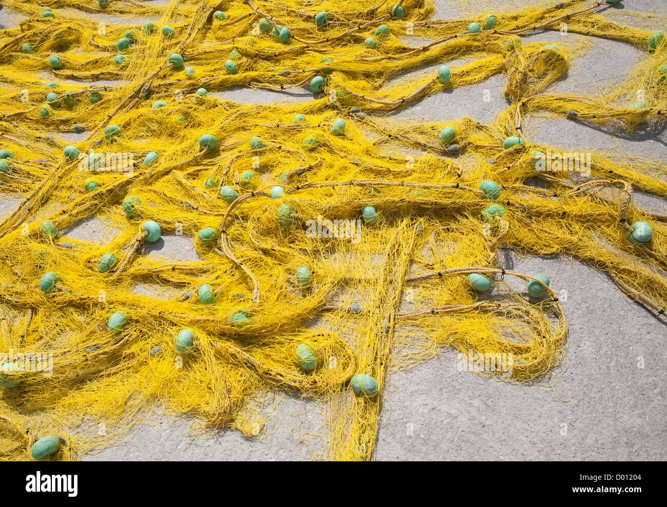 closeup of yellow fishing net with blue float laying on the ground ...