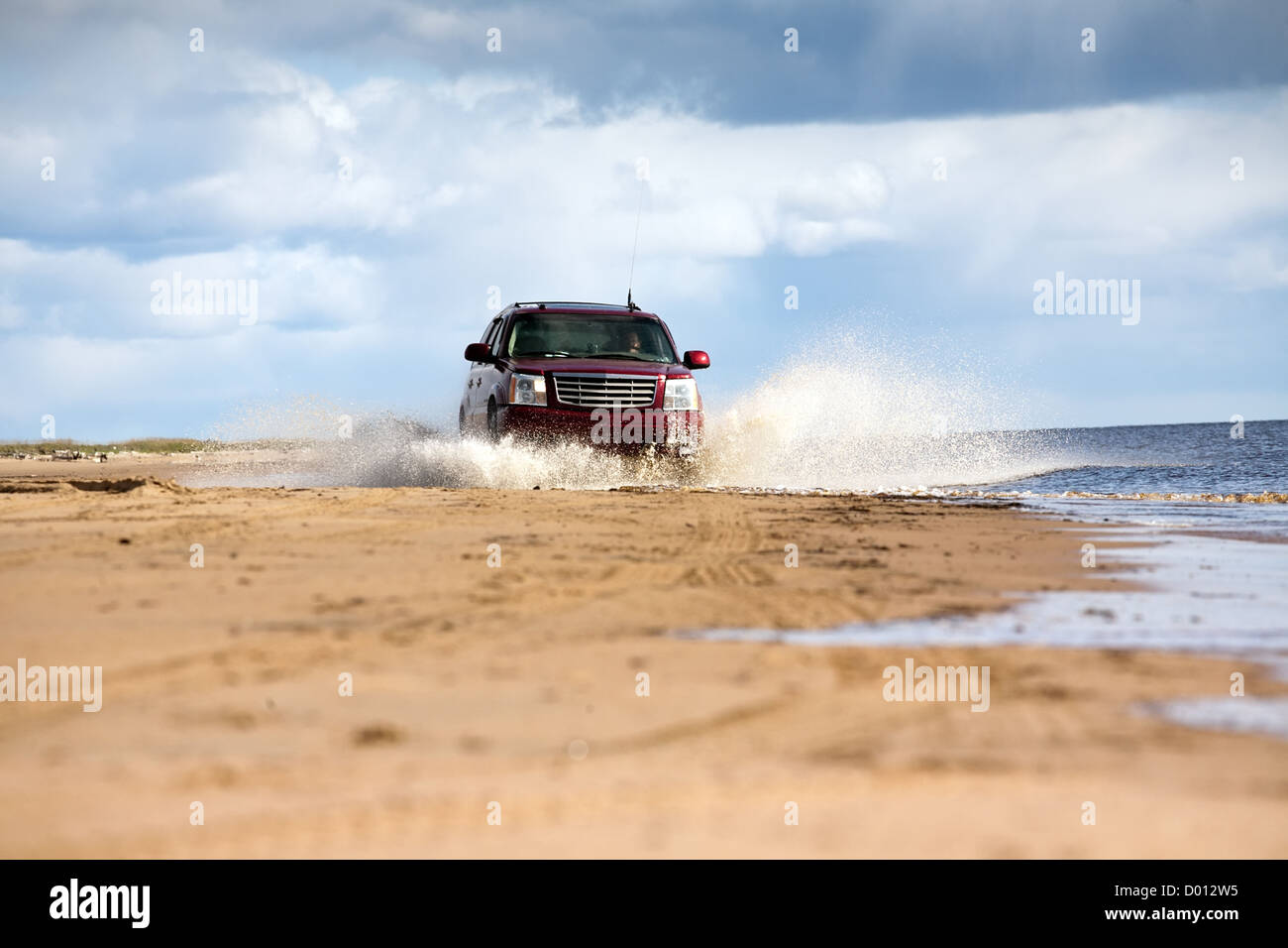 big four-wheel car driving on sandy sea coast in water splashes Stock ...