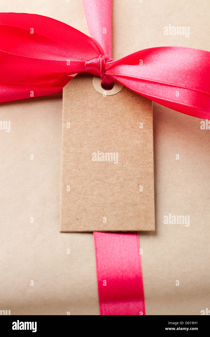 Close-up of a simple gift package with a red ribbon and small card ...