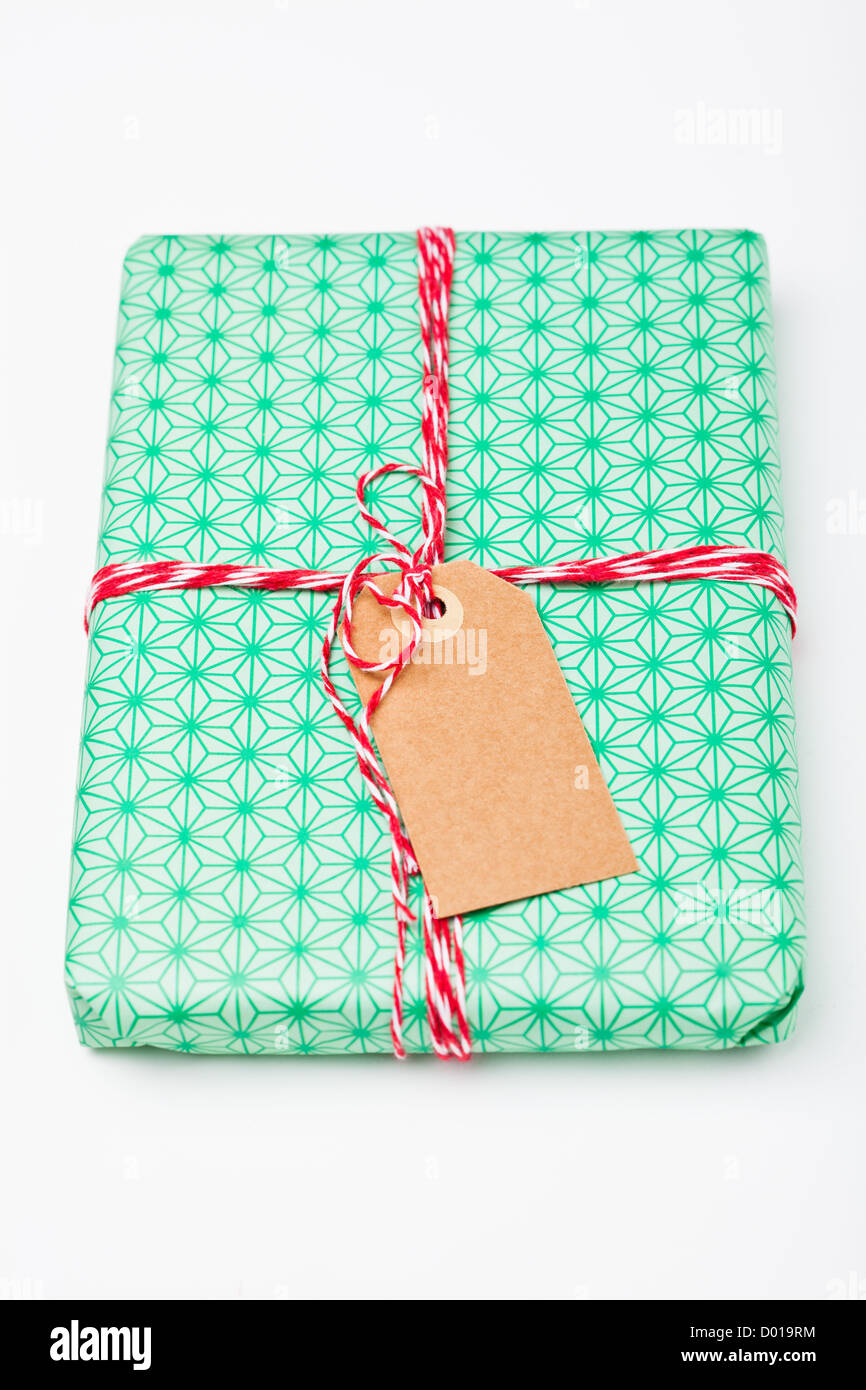 Simple gift wrapped in green paper with plain cardboard tag on white ...