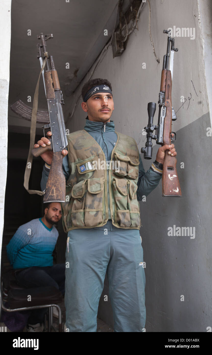 Aleppo, Syria: A Free Syrian Army member holds up rifles while a ...