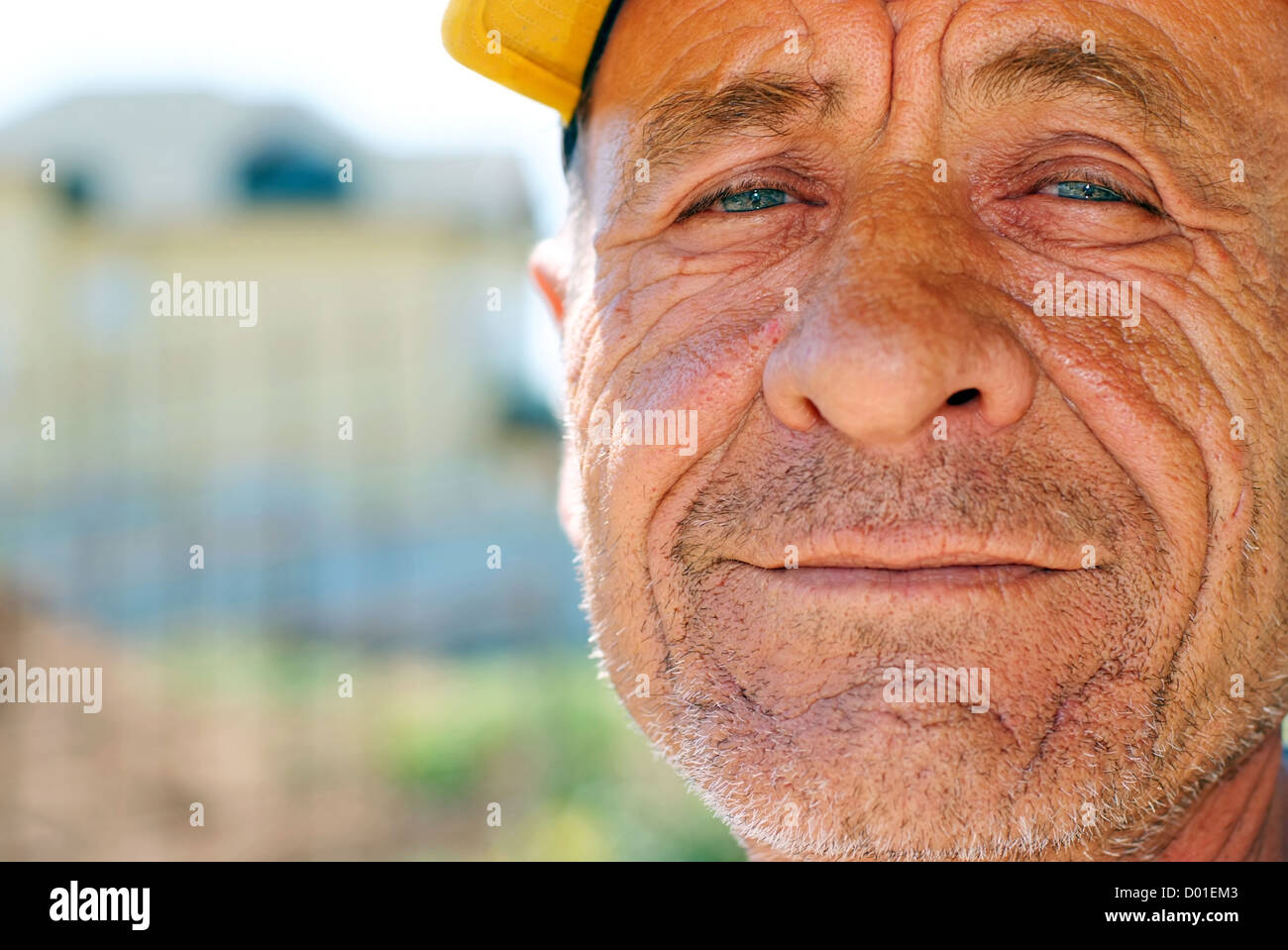 Old wrinkled man with yellow cap against blurry background Stock Photo ...