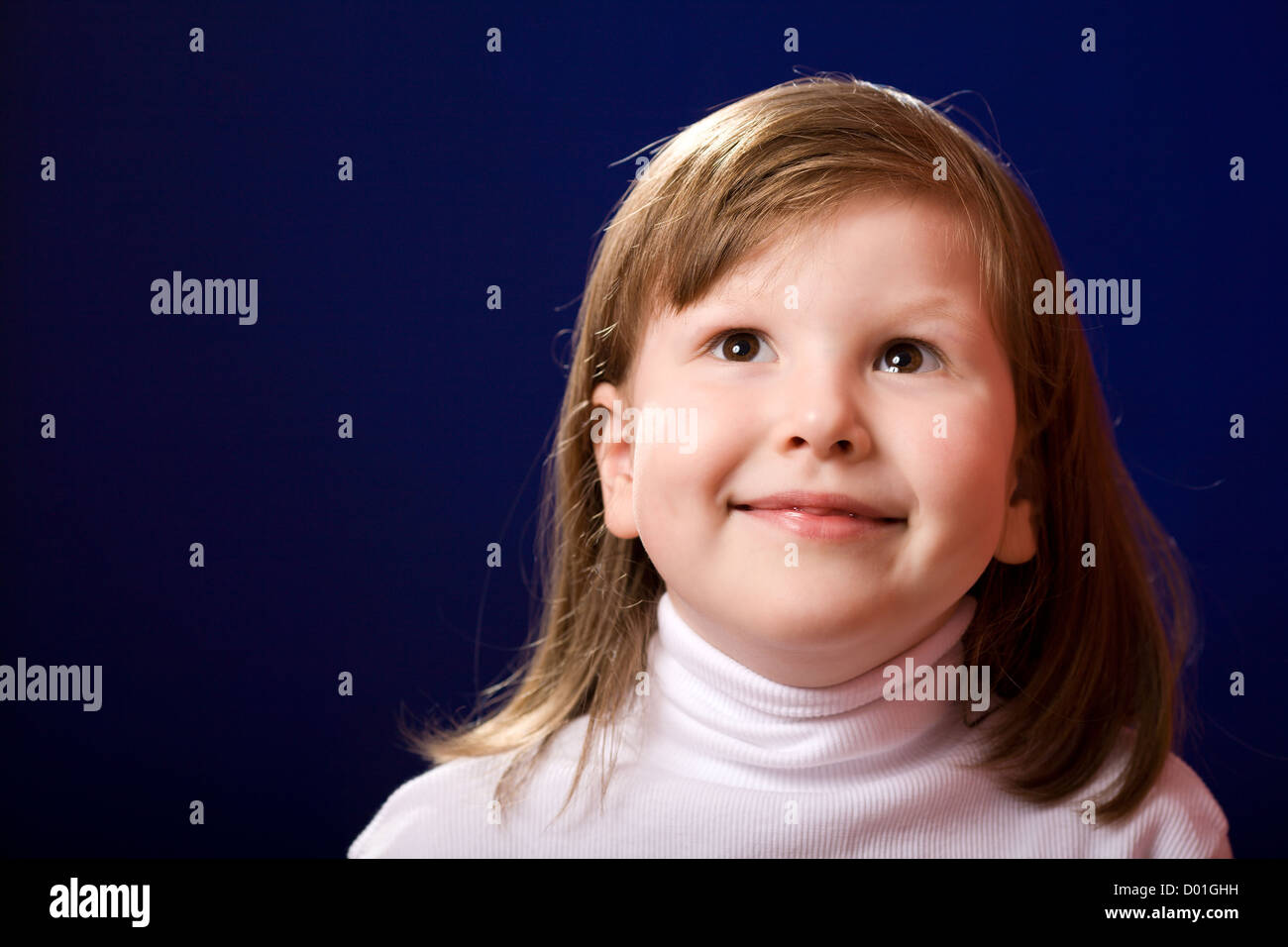Happy Child looking up with interest over dark blue background Stock ...