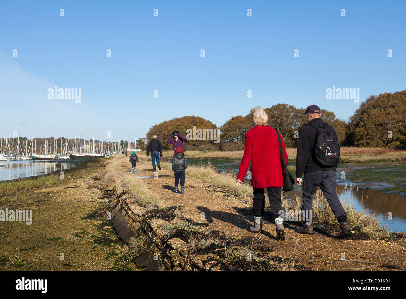 Family out for a winter walk on a path alongside the River Hamble ...