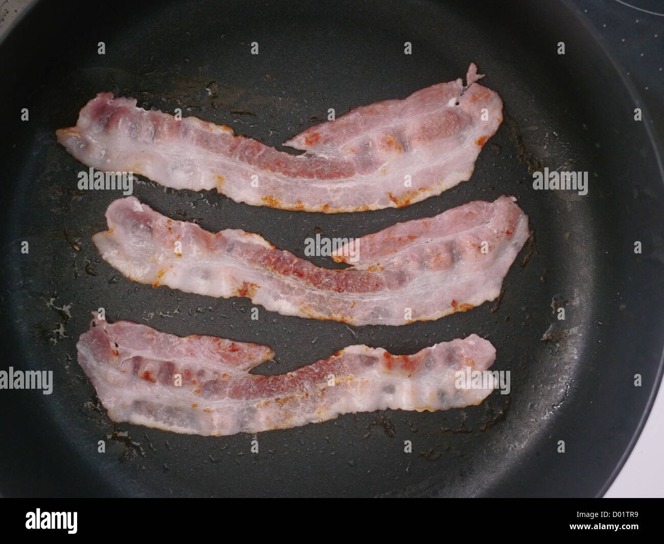 strips of bacon frying in a skillet Stock Photo - Alamy
