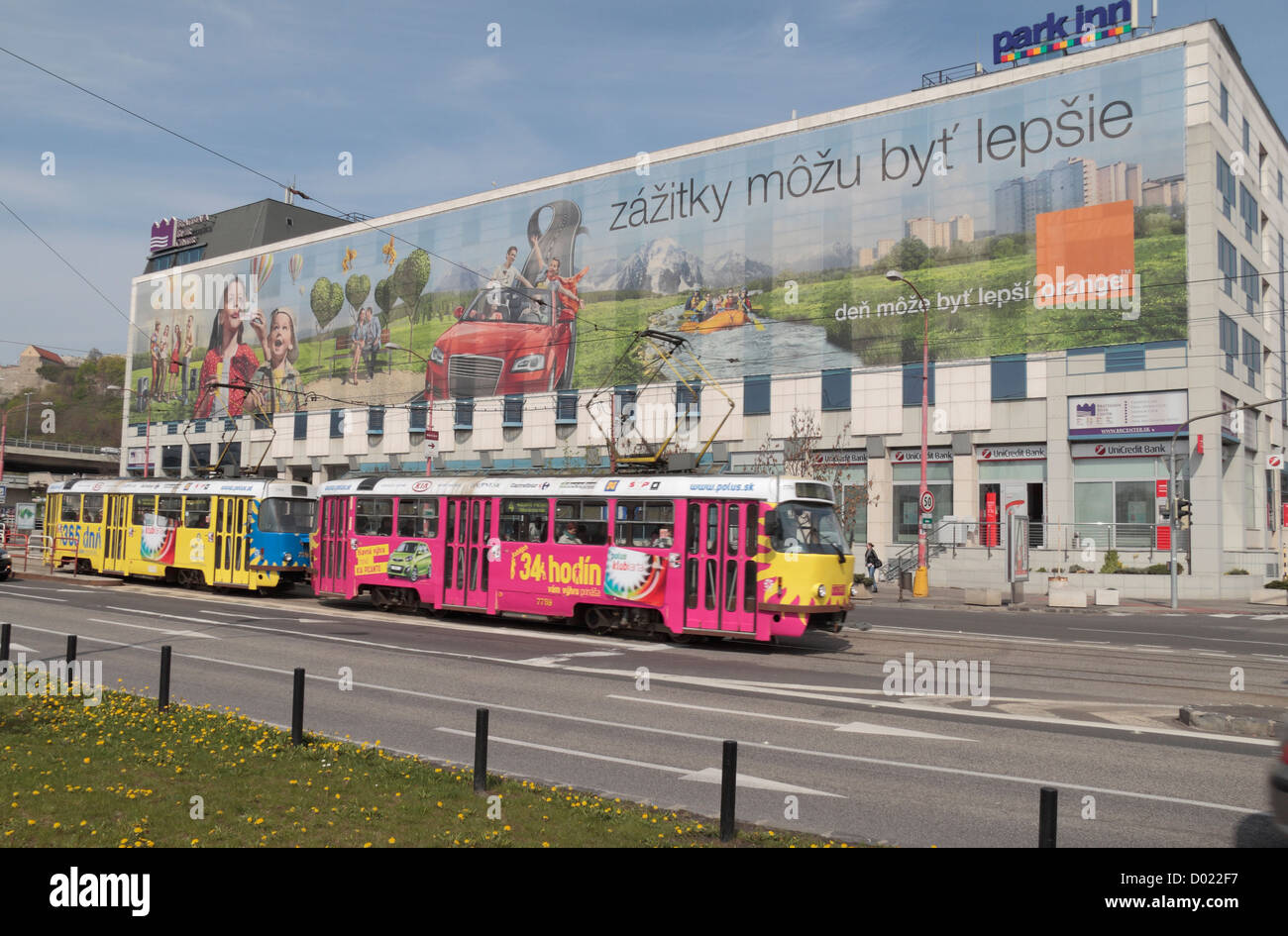 Colourful tram passing a massive advertising billboard on the side of a ...