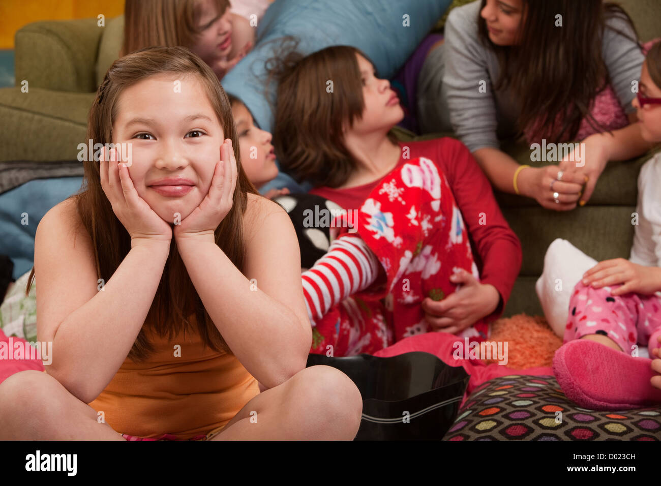 Happy girl with friends seated on floor at a sleepover Stock Photo - Alamy
