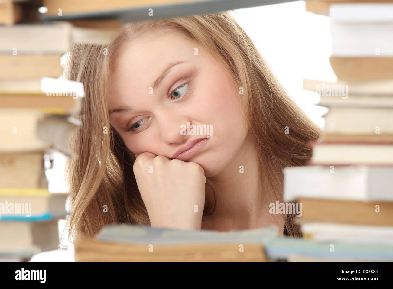 Young woman sitting behind books - tired Stock Photo - Alamy