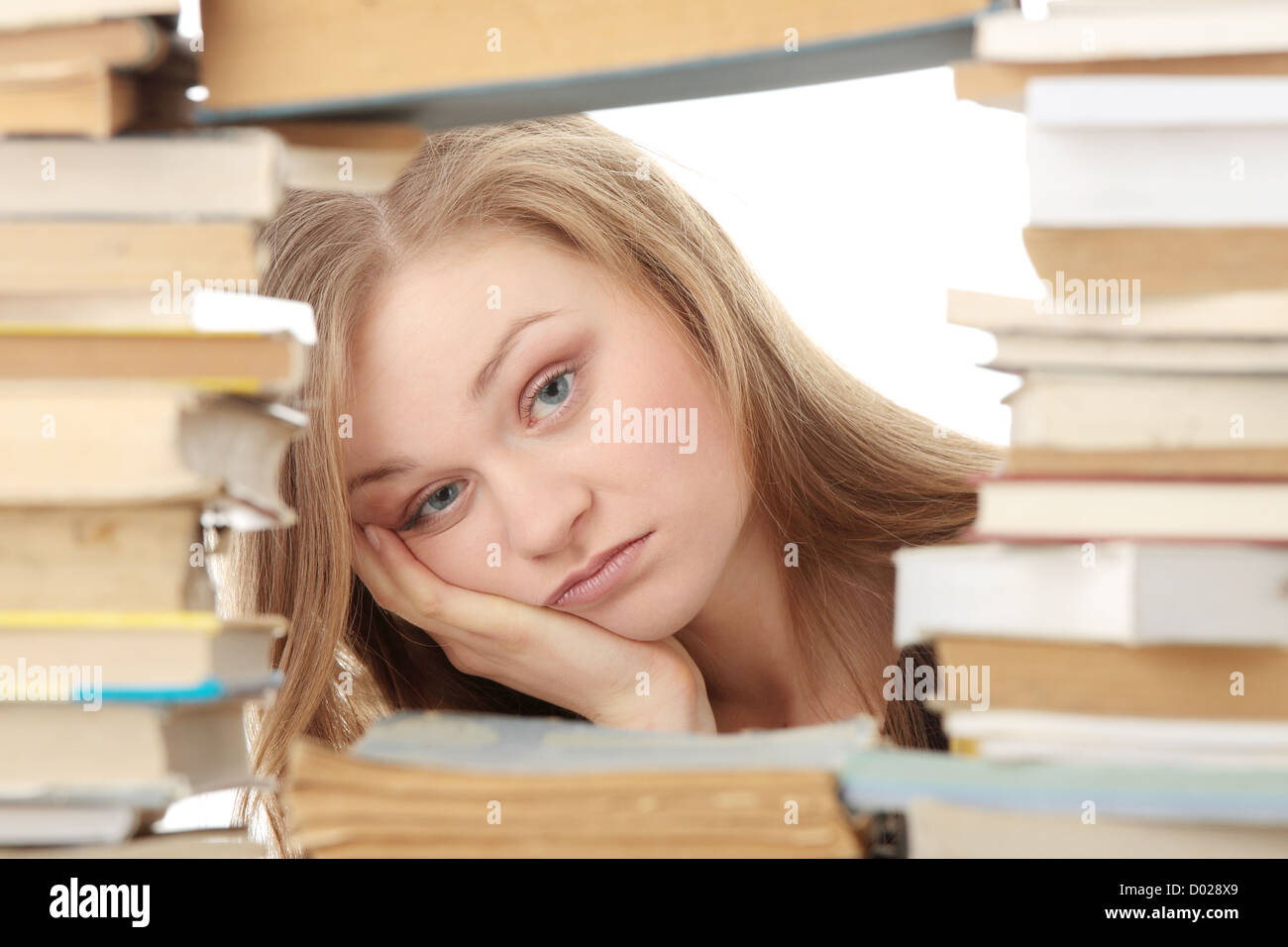 Young woman sitting behind books - tired Stock Photo - Alamy
