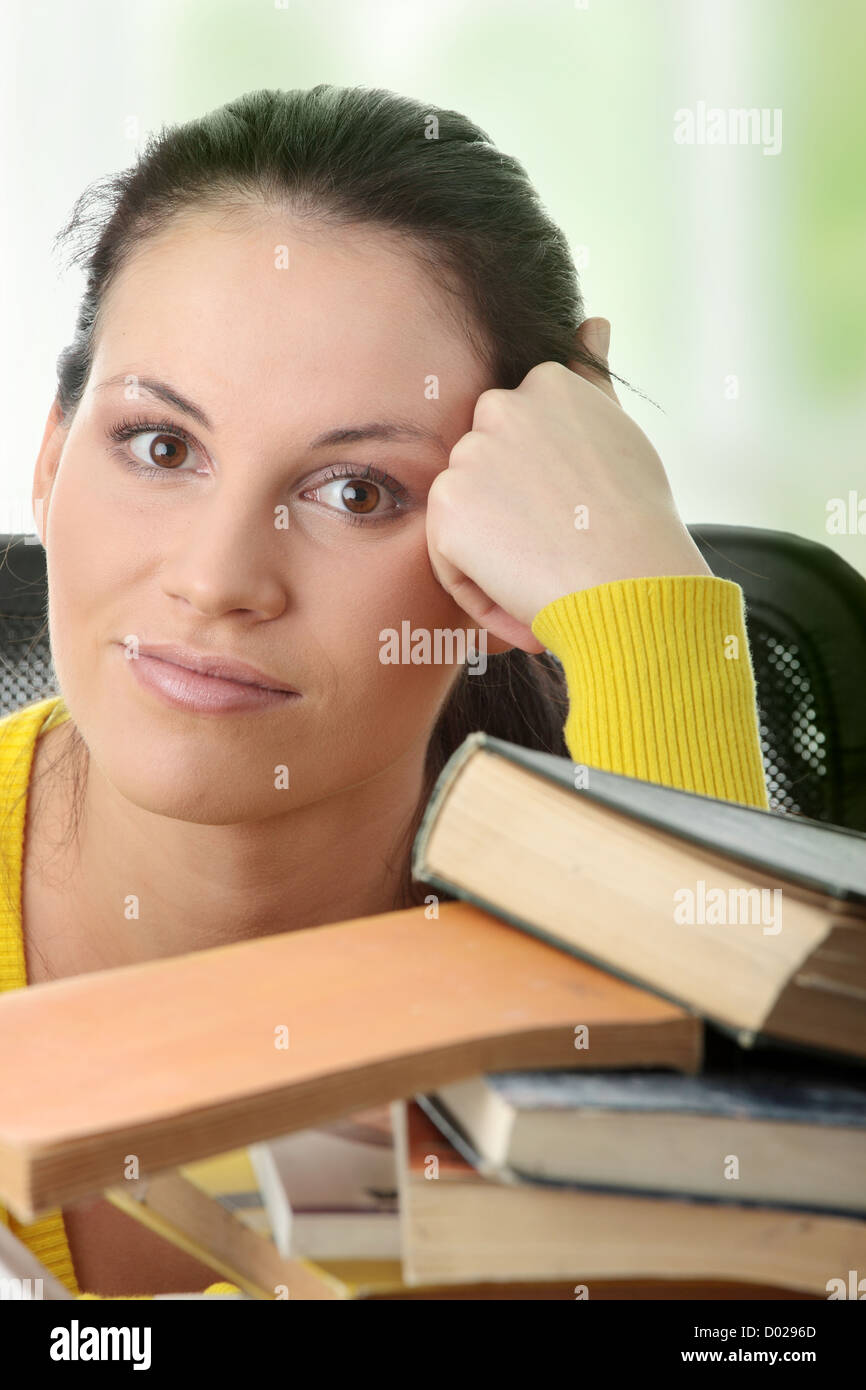 Young woman sitting behind books Stock Photo - Alamy