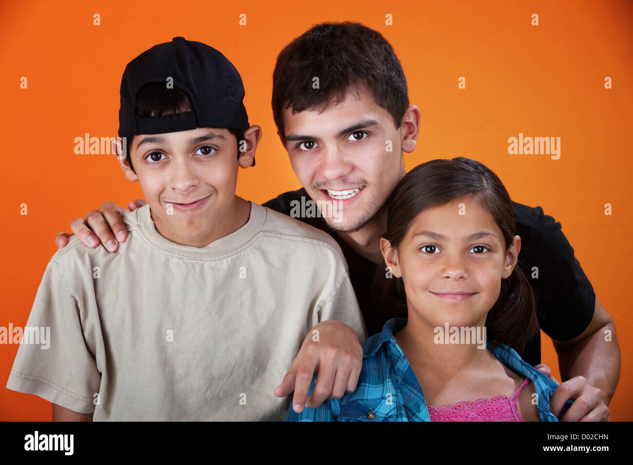 Smiling brothers and sister on an orange background Stock Photo - Alamy