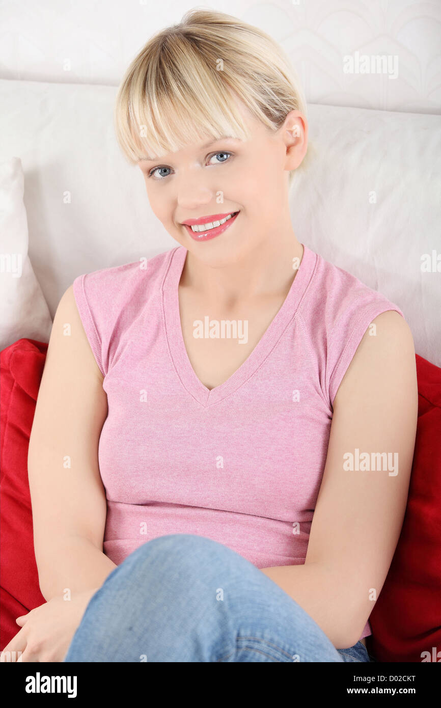 Beautiful young woman sitting on the couch. Indoor Stock Photo - Alamy