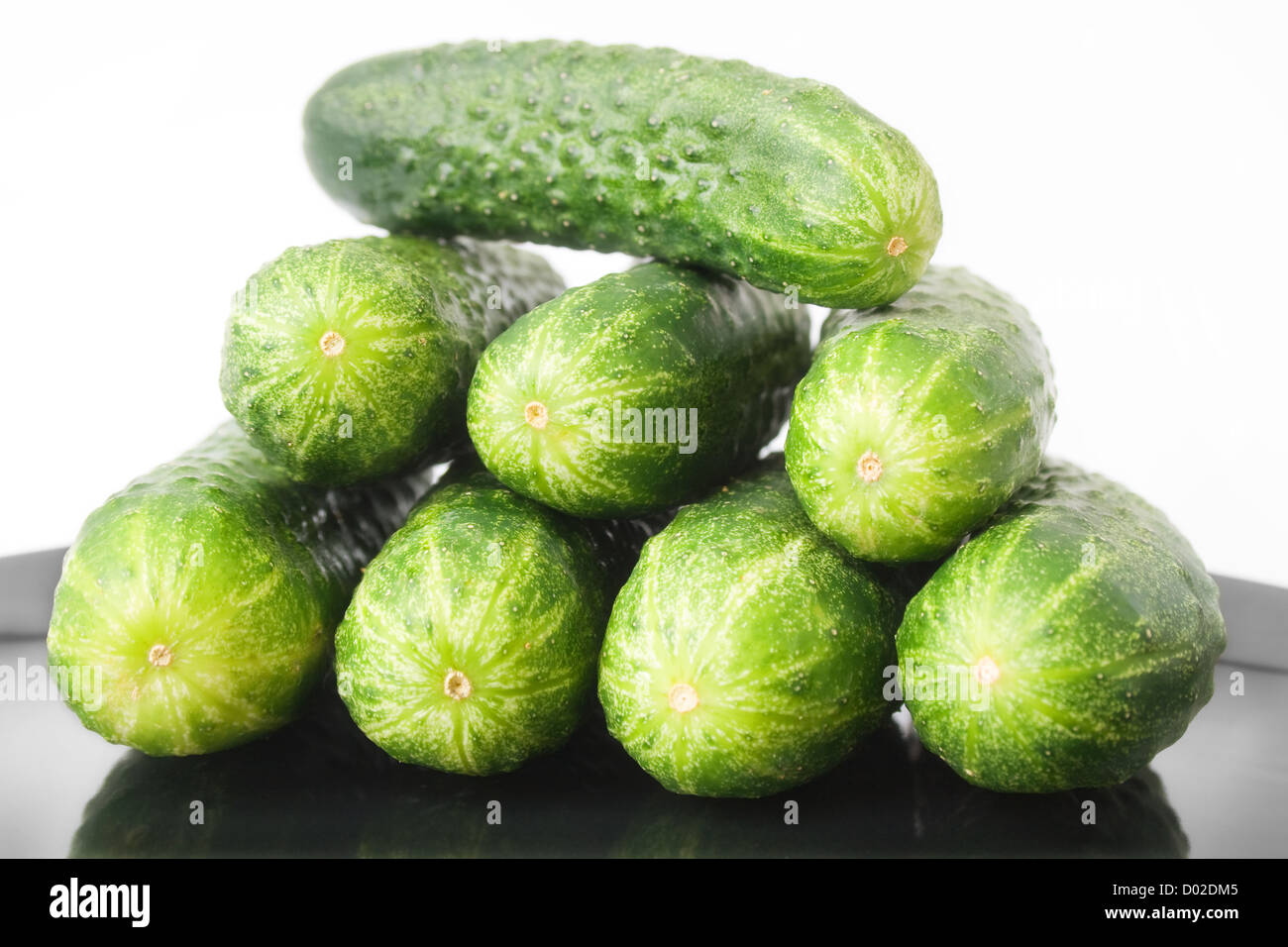 cucumbers placed in a black ceramic plate isolated on white background ...