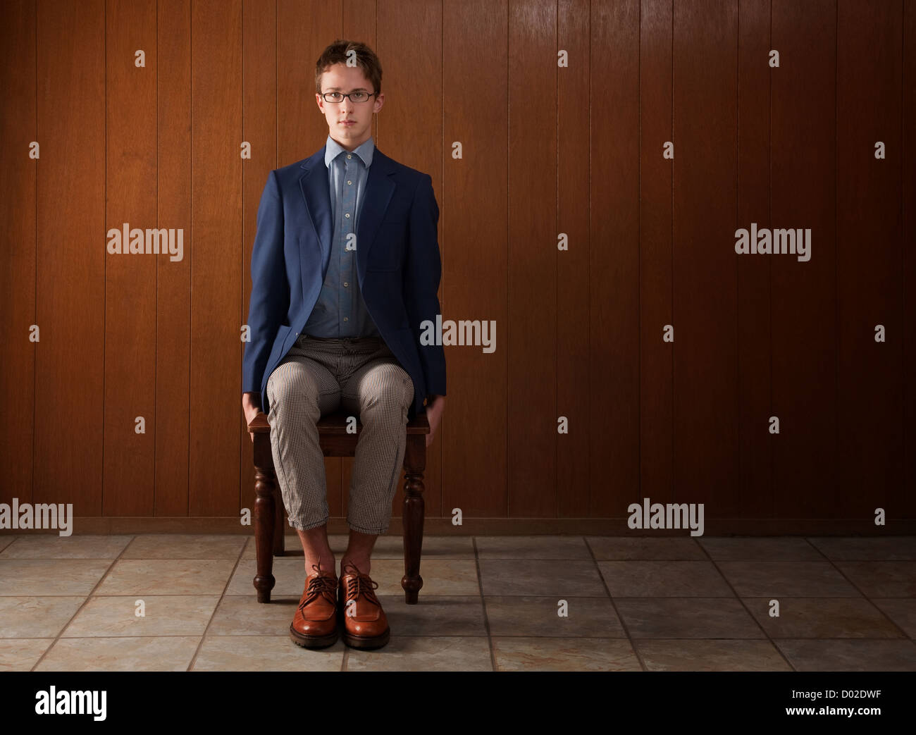 Stiff young Caucasian man sitting on wooden chair Stock Photo - Alamy