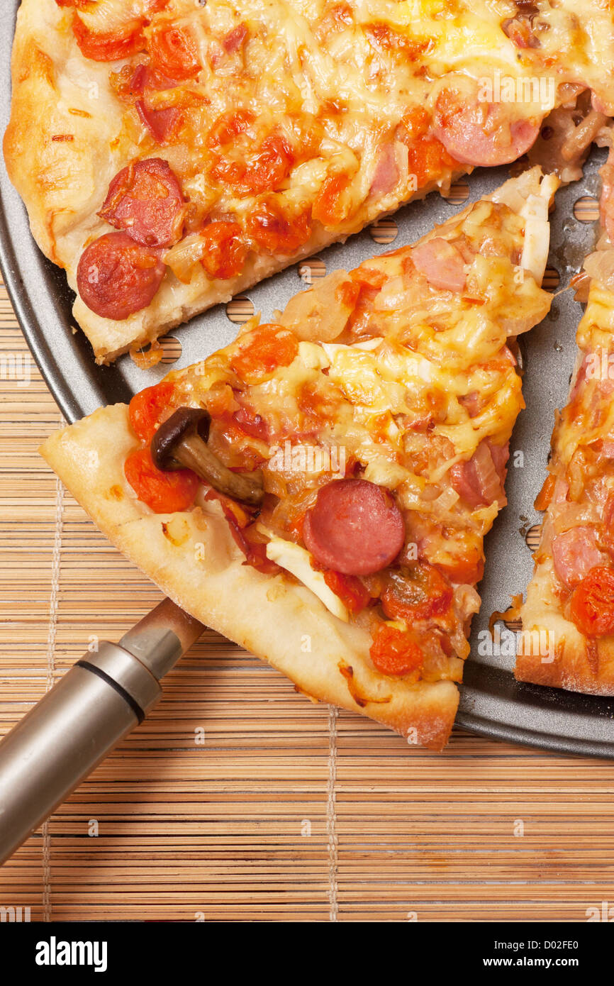 A slice of pizza is lifted from the pan with a spatula Stock Photo - Alamy