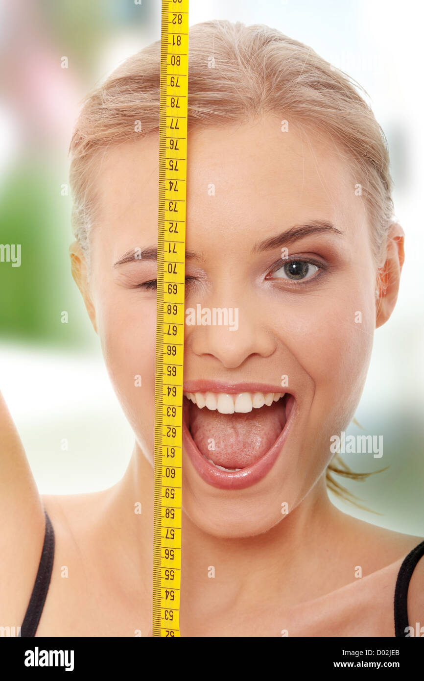 Beautiful young caucasian woman measuring her body with tape, isolated ...