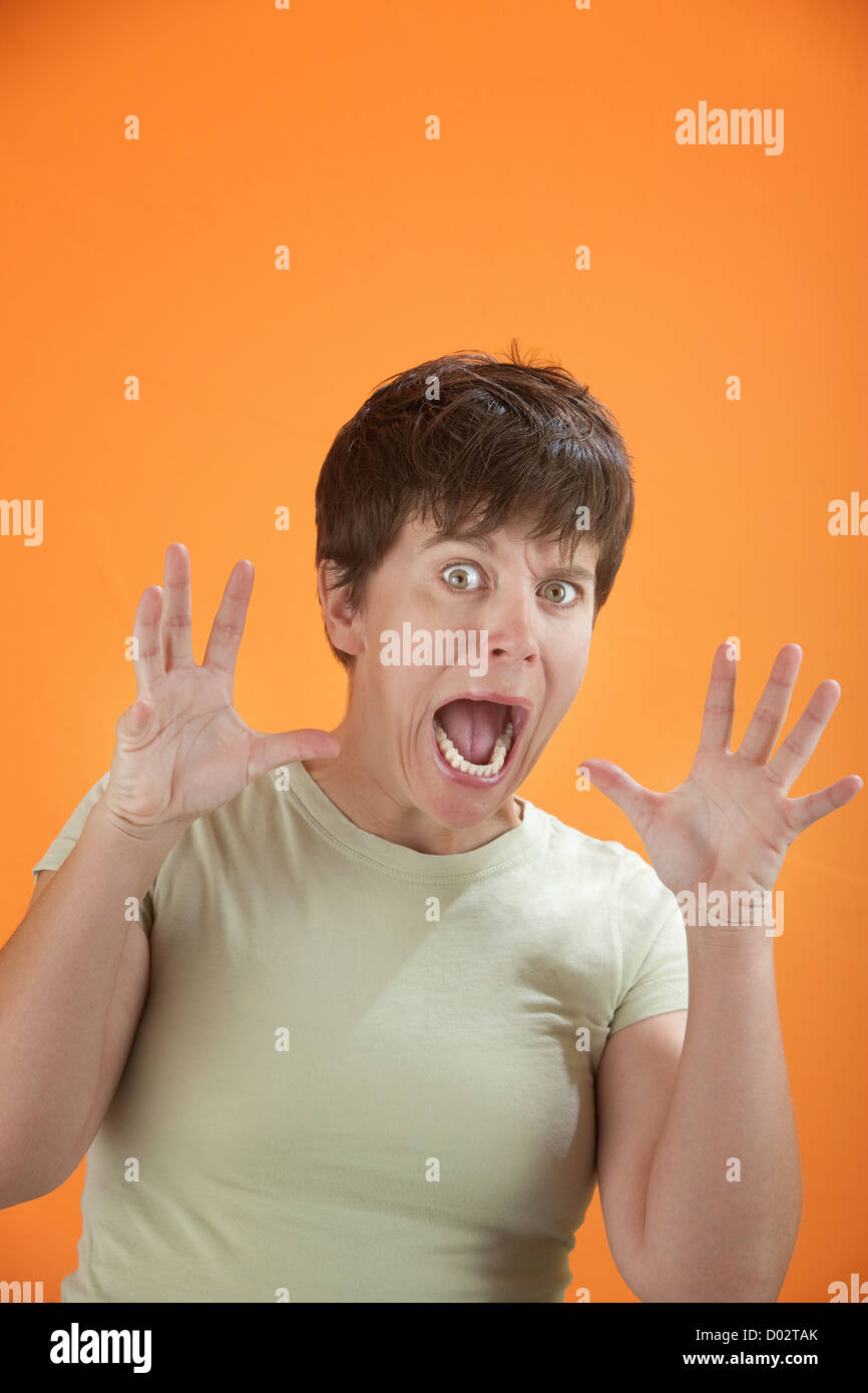 Young woman with hands near face looking horrified Stock Photo - Alamy