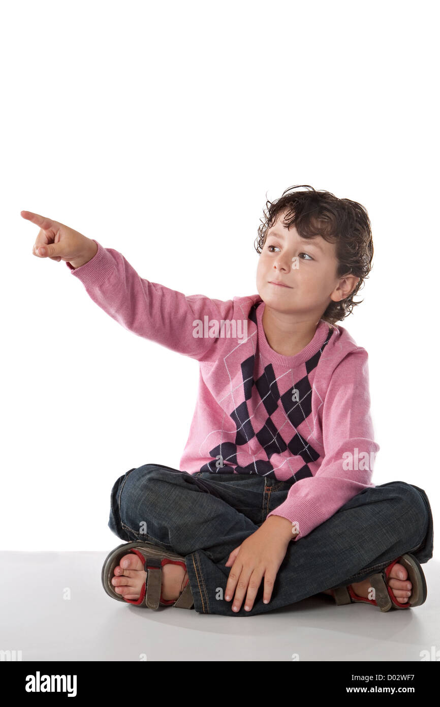Beautiful child pointing with his finger sitting on a over white ...