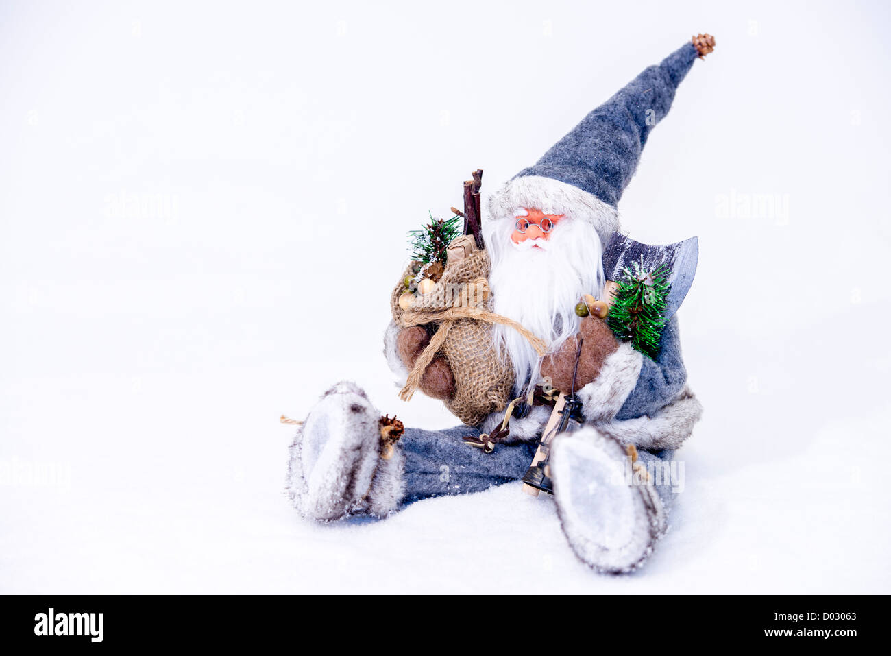 Santa Claus sitting on snowy ground, holding a big gift bag a axe and a ...