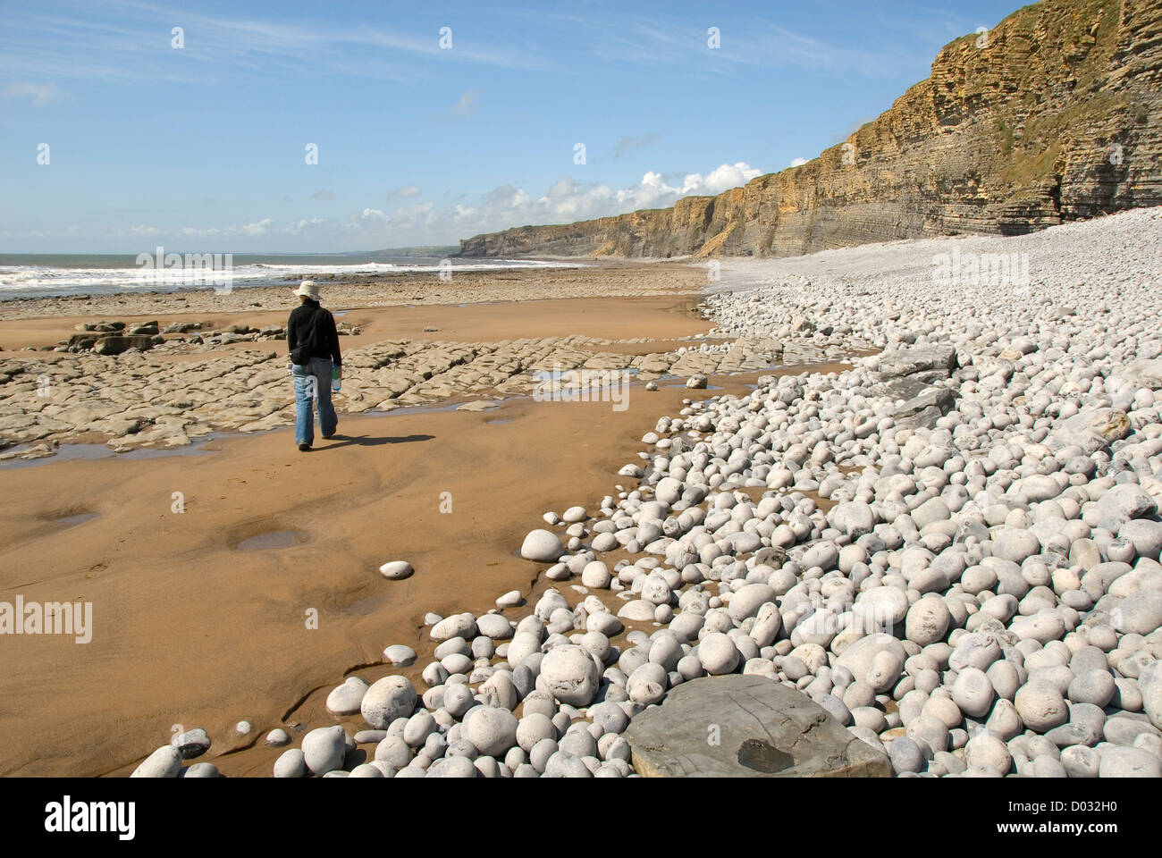Woman walking along the beach close to steep cliffs, close to Nash ...