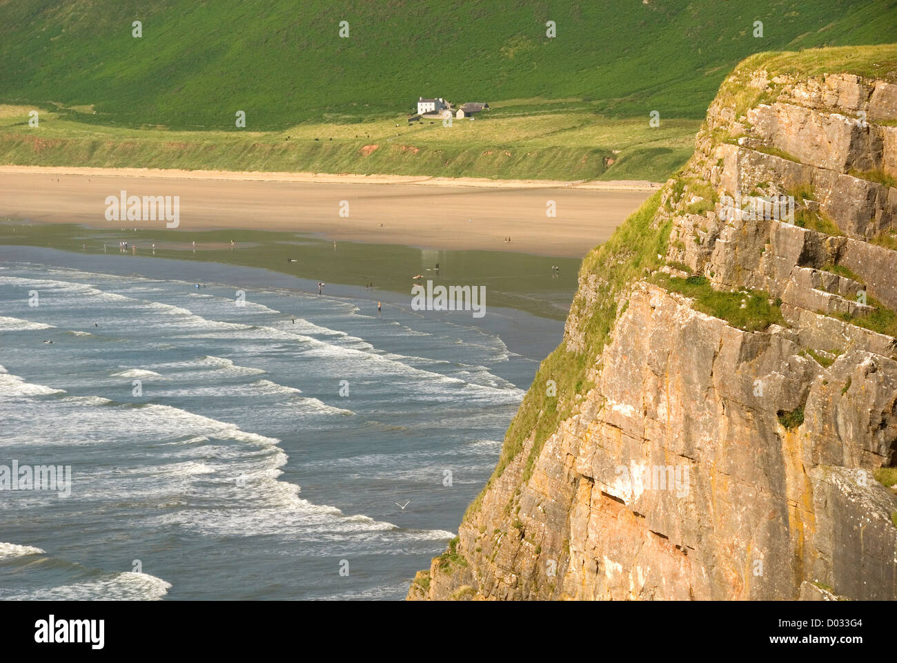 Steep cliff, breaking waves and people at Rhossili beach, Gower ...