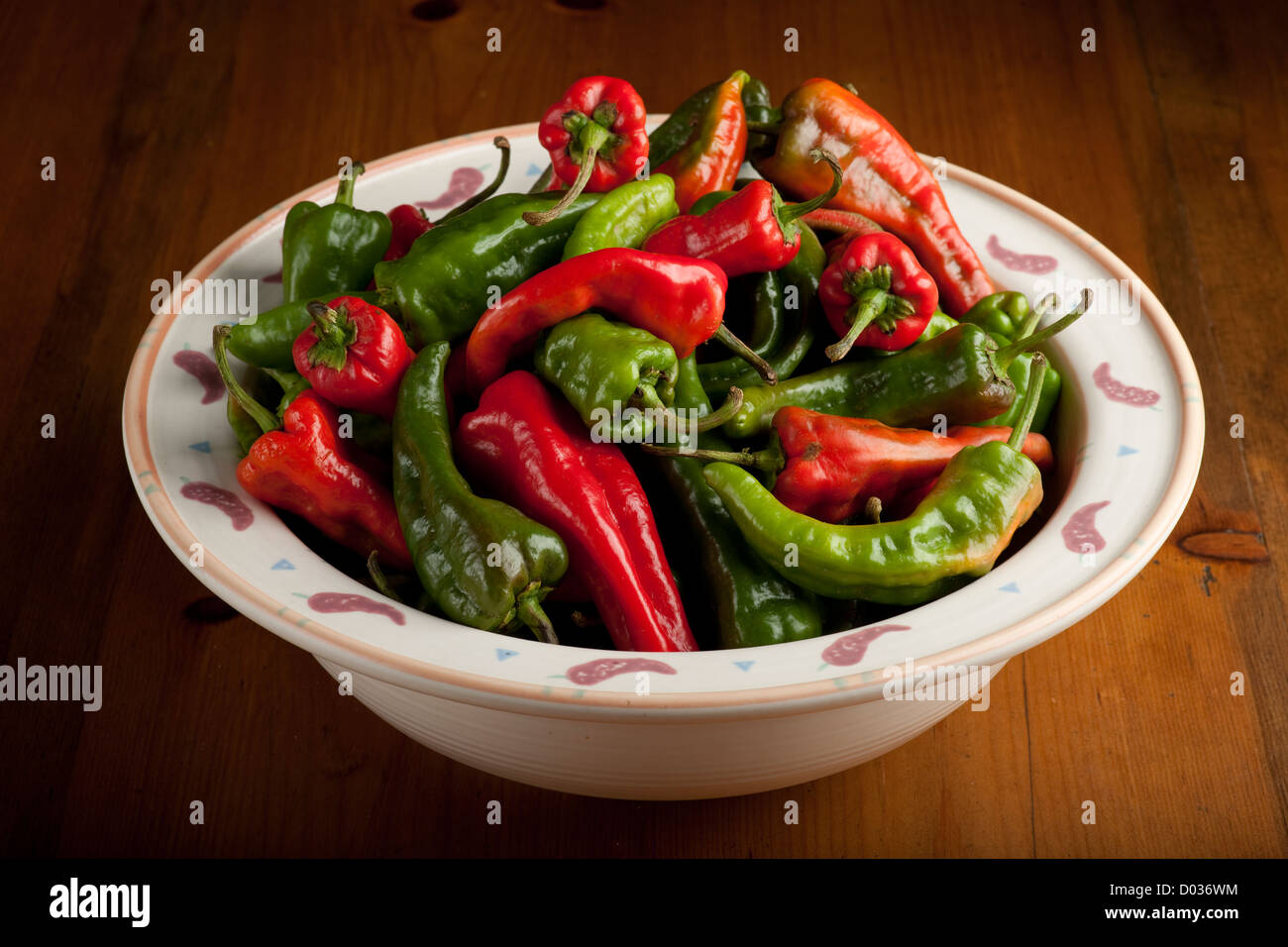 Southwestern style bowl of green and red chili peppers on a rustic wood ...