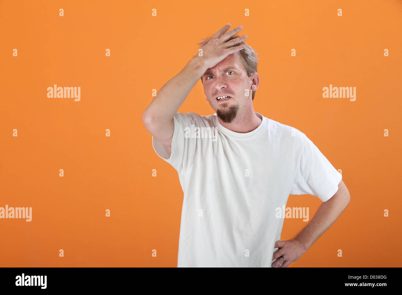 Tense Caucasian man with hand on his forehead on an orange background ...