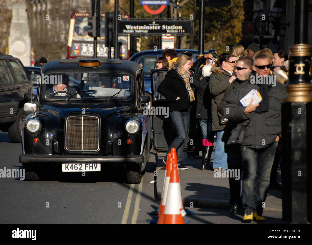 Black taxi and passenger, crowded pavement, Westmister, London, England ...