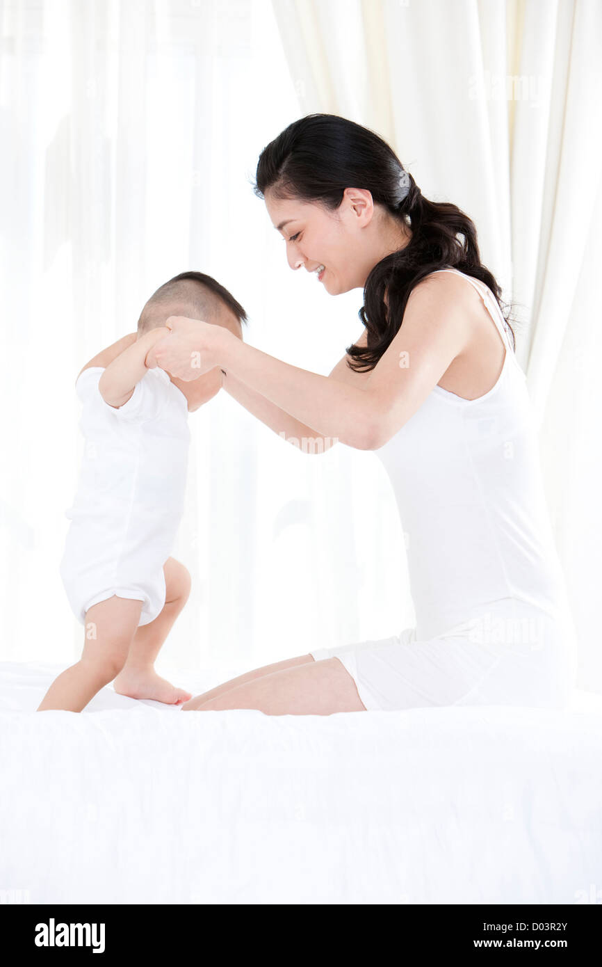 Mother helping little baby to stand up Stock Photo - Alamy