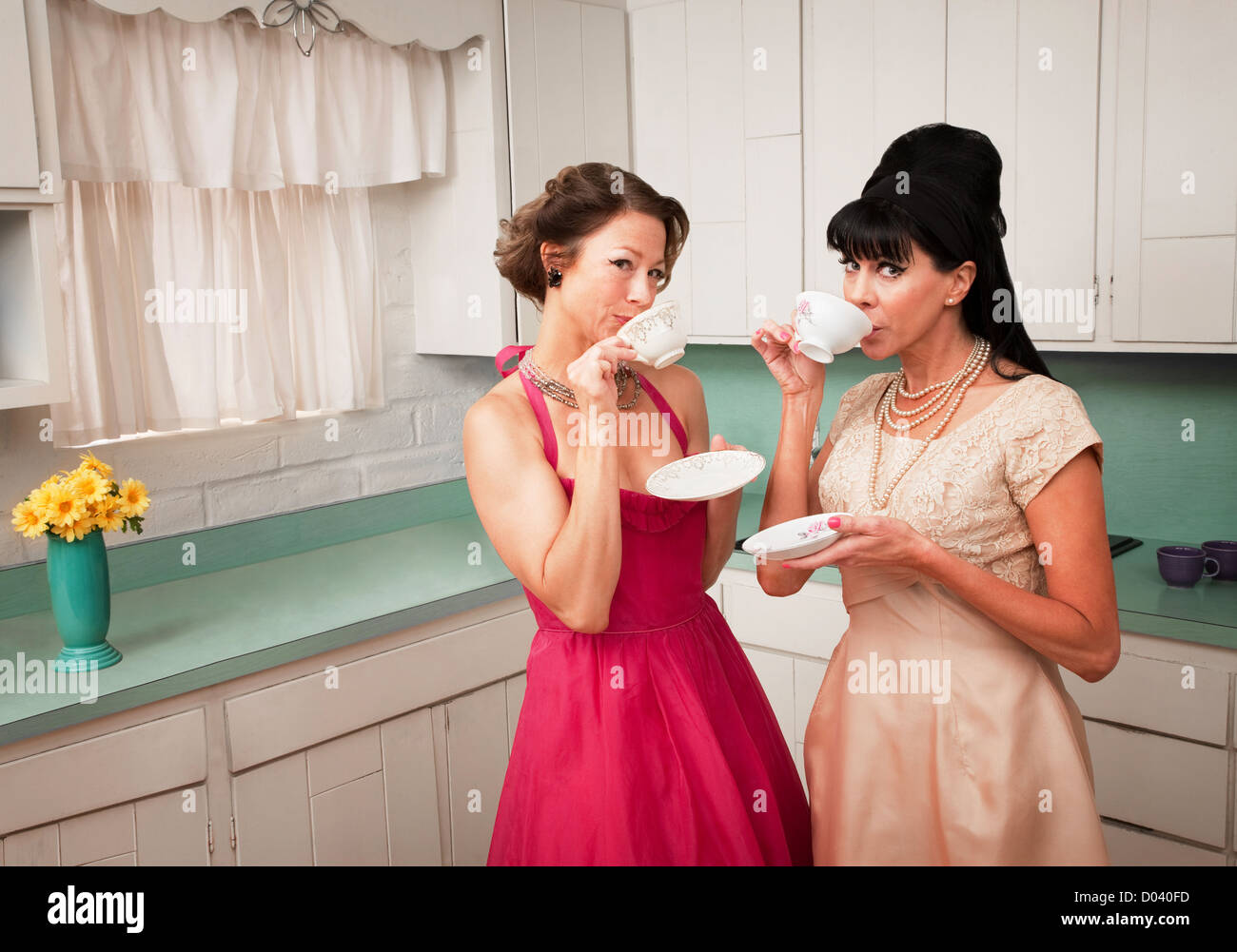 Two retro-styled women drinking coffee in kitchen Stock Photo - Alamy