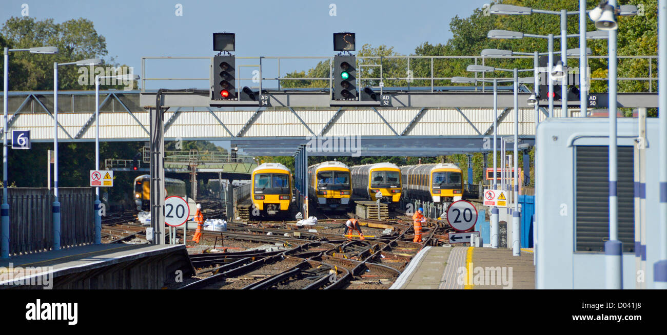 Railway maintenance workers on live tracks with trains in depot beyond ...