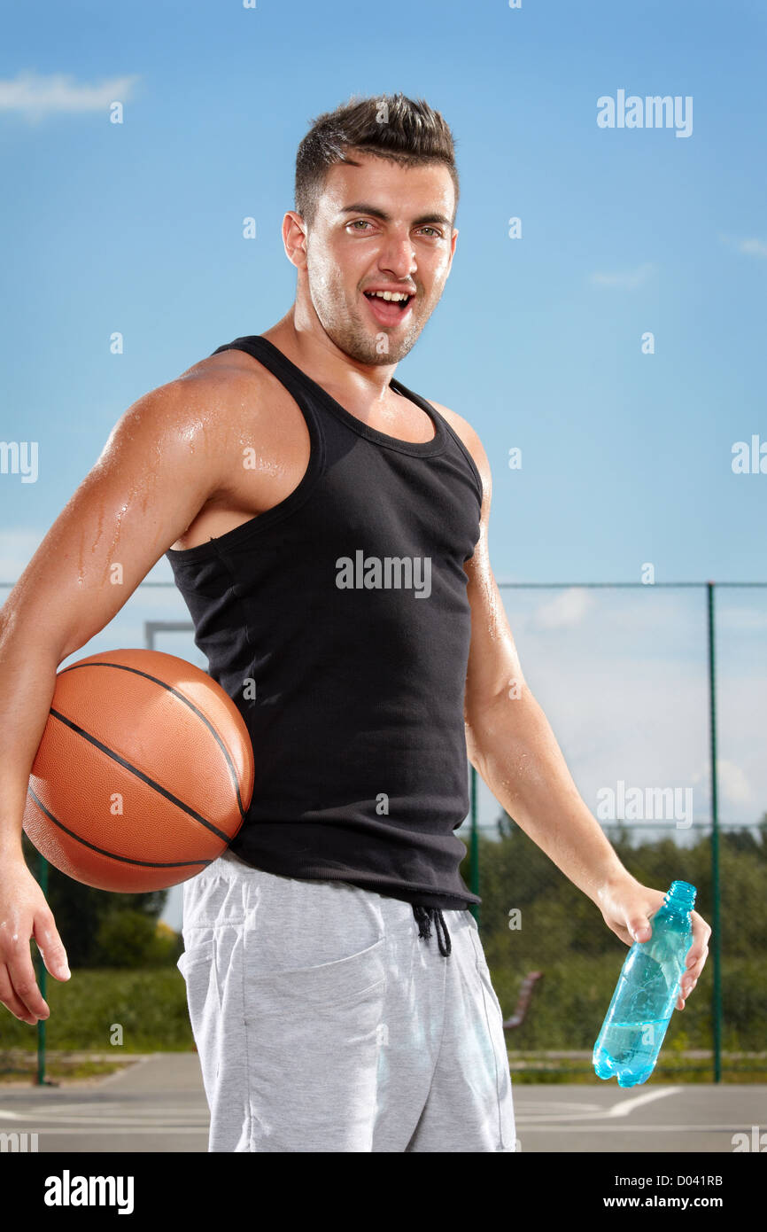 Thirsty basketball player drinking water on sports field Stock Photo ...