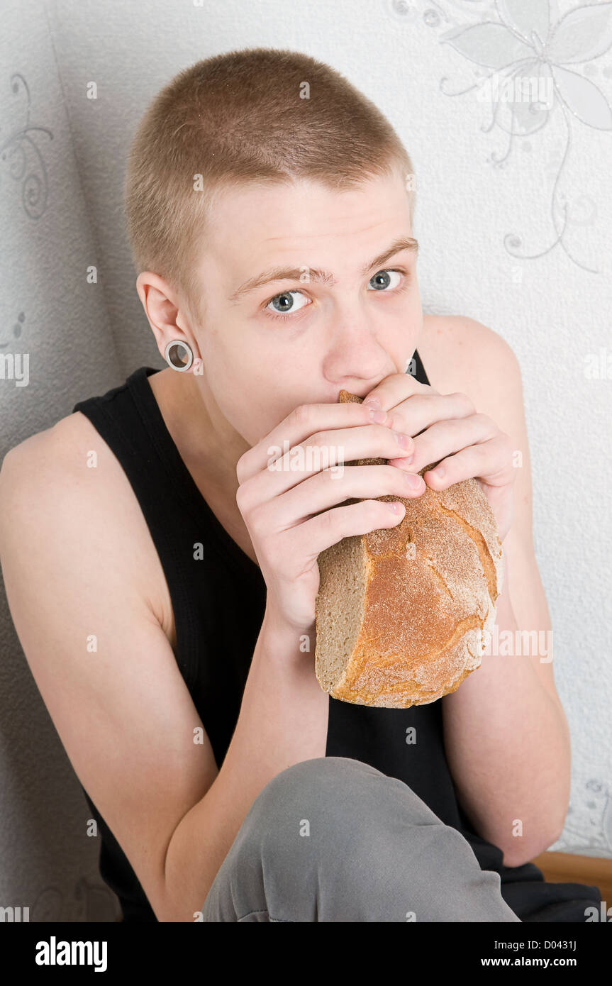 hungry teenager sitting in the corner and eat bread Stock Photo - Alamy