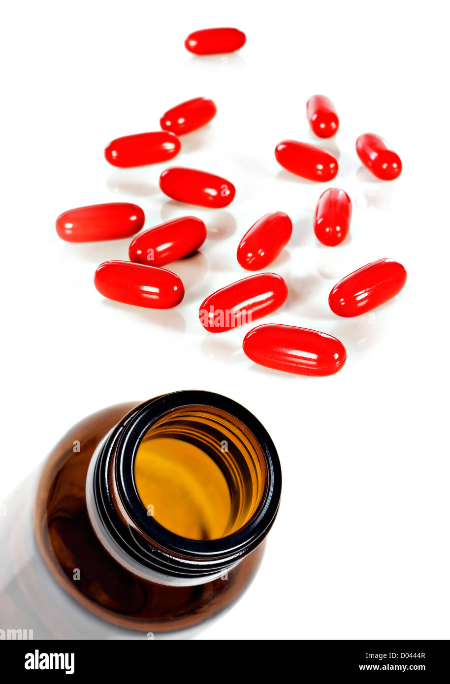 Red pills and pill bottle on white Stock Photo - Alamy