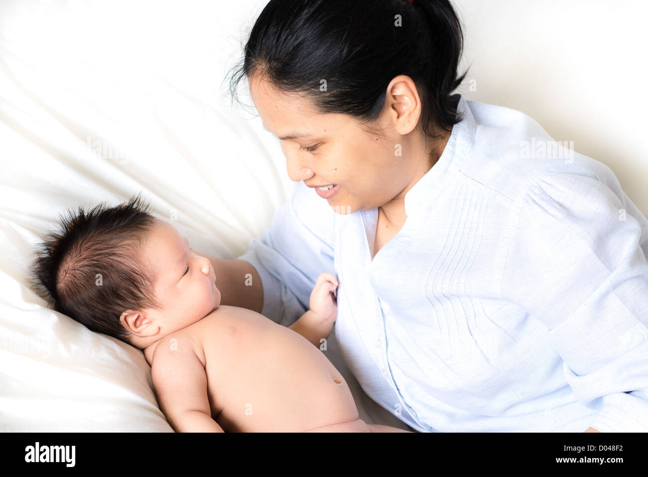 Mother and newborn baby together on a white bed Stock Photo - Alamy