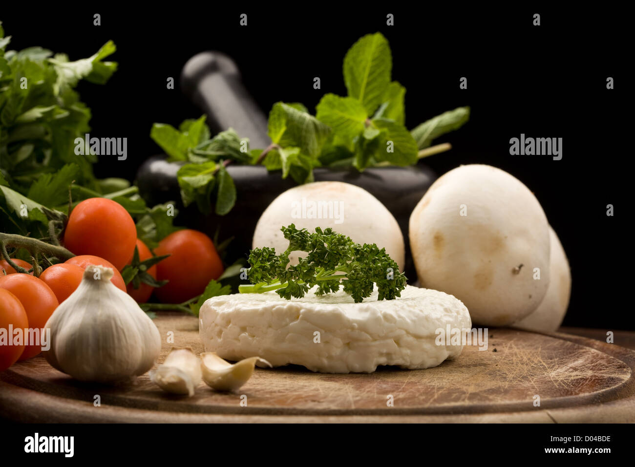 photo of fresh round ricotta cheese with vegetables arround on wood ...