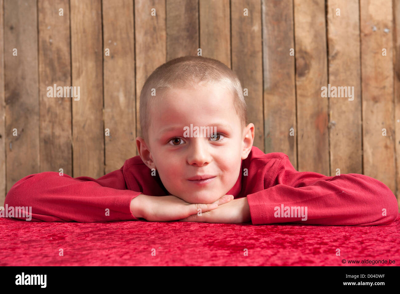 little boy, head resting on his arms, wooden background Stock Photo - Alamy