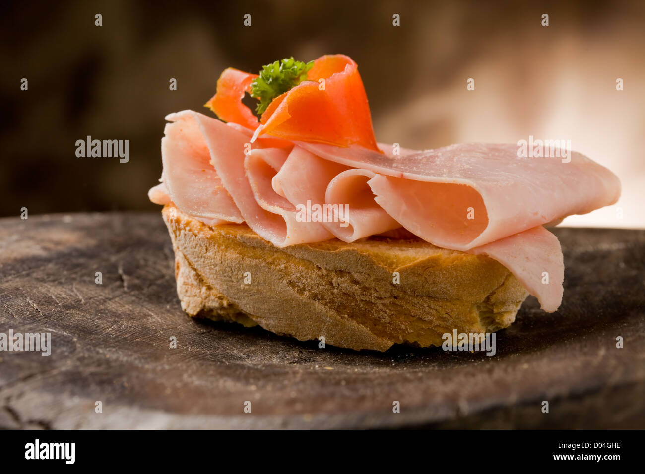 photo of sliced bread with ham and tomato on wooden table Stock Photo ...