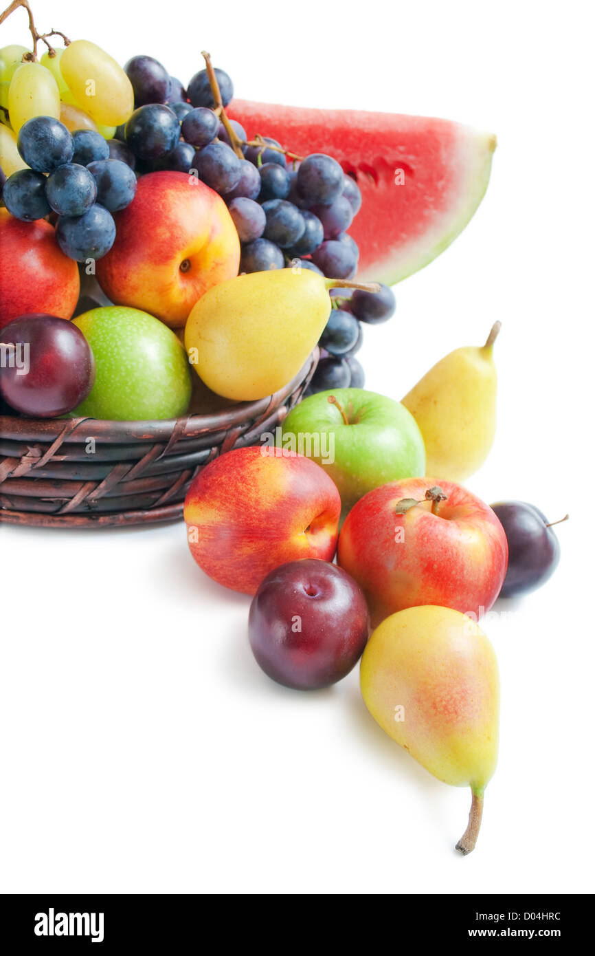 Various fresh ripe fruits placed in a wicker basket and around on white ...