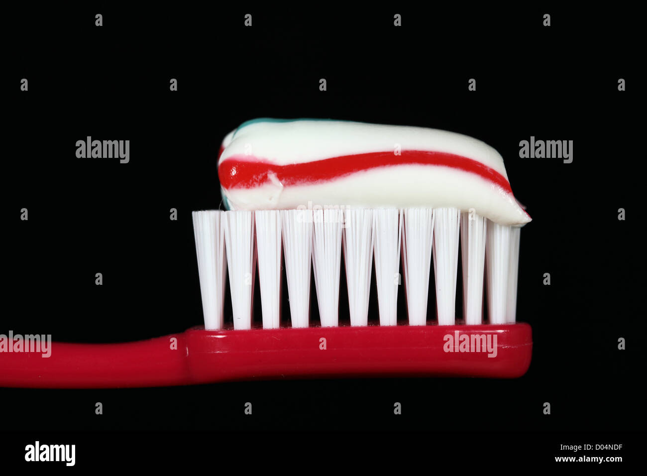 A red toothbrush on a black background, with a striped toothpaste Stock ...