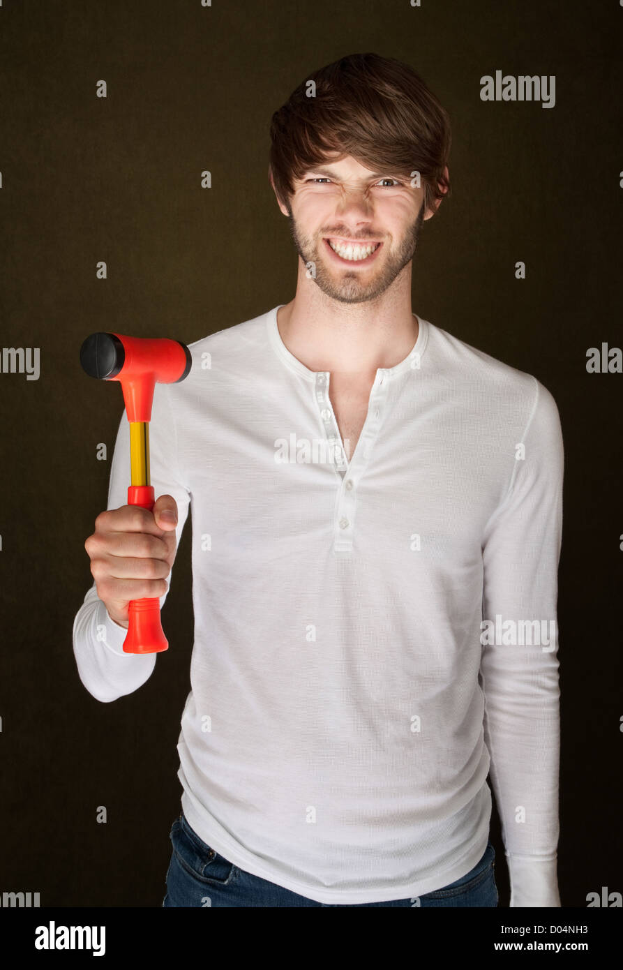 Smiling young Caucasian male with red mallet Stock Photo - Alamy
