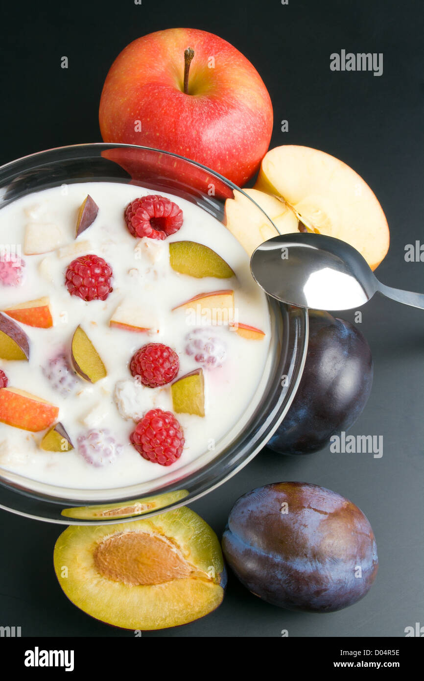 Glass bowl filled with yogurt mixed with fruit pieces arranged with ...