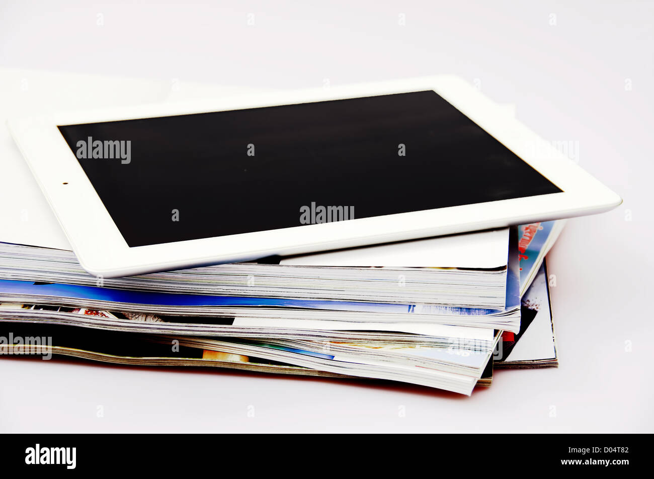 A white tablet on top of a stack of magazines Stock Photo - Alamy