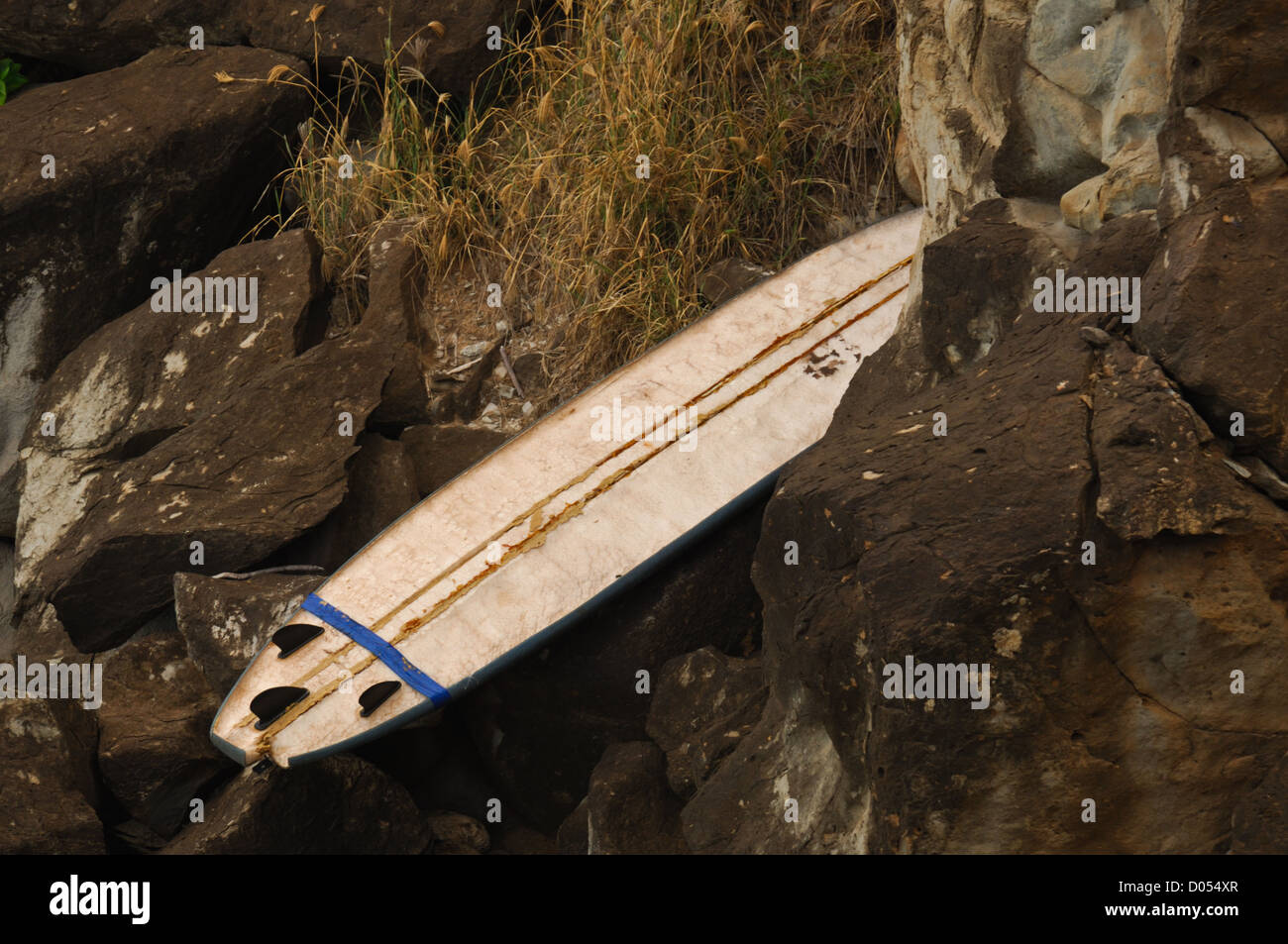 Wrecked and abandoned surfboard lying in on the rocks at Honolua Bay ...