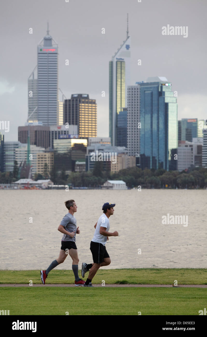 Two men jogging on path beside river with city in the background Stock ...