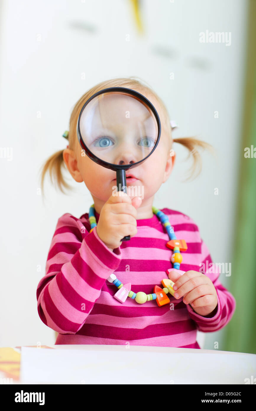 Toddler girl playing with magnifier Stock Photo - Alamy