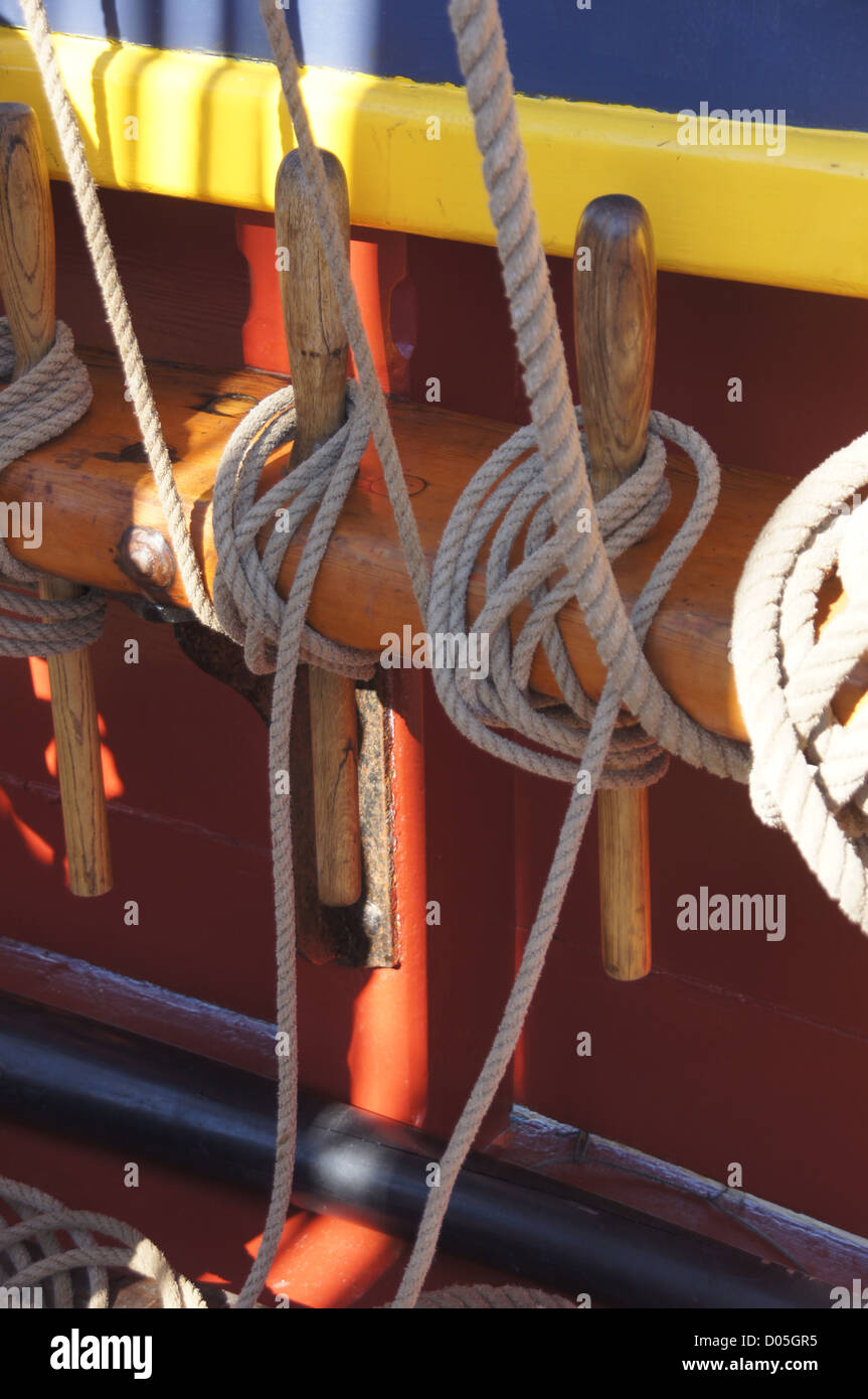 Coiled rope lines stored on belaying pins on a wooden tall ship Stock ...