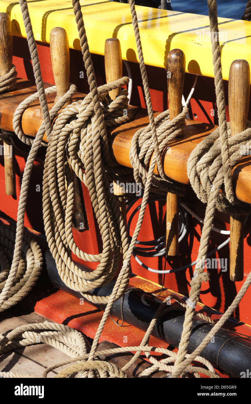 Coiled rope lines stored on belaying pins on a wooden tall ship Stock ...