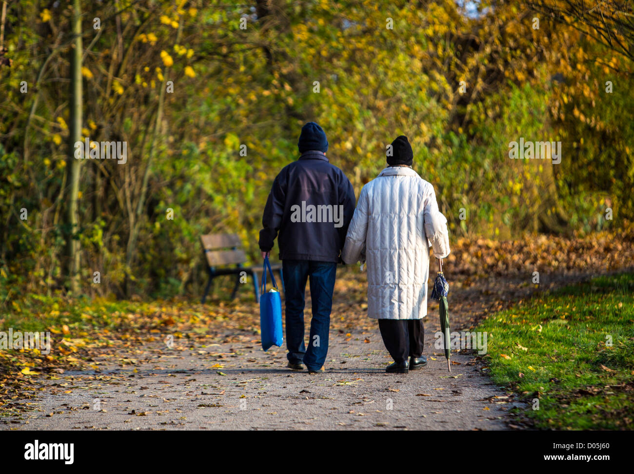 Two older people, seniors, retired, take a walk in fall, along a ...