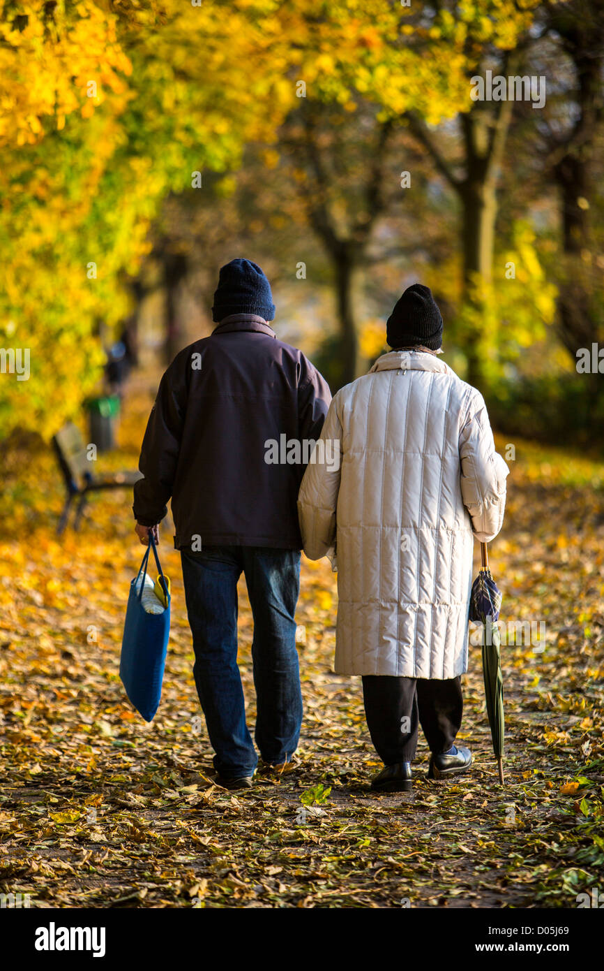 Two older people, seniors, retired, take a walk in fall, along a ...